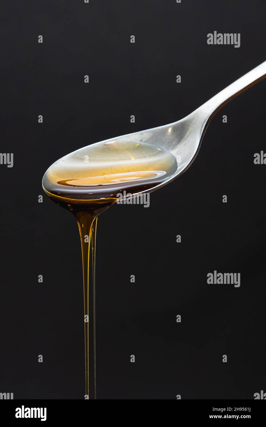 Honey dripping from spoon on dark background Stock Photo - Alamy