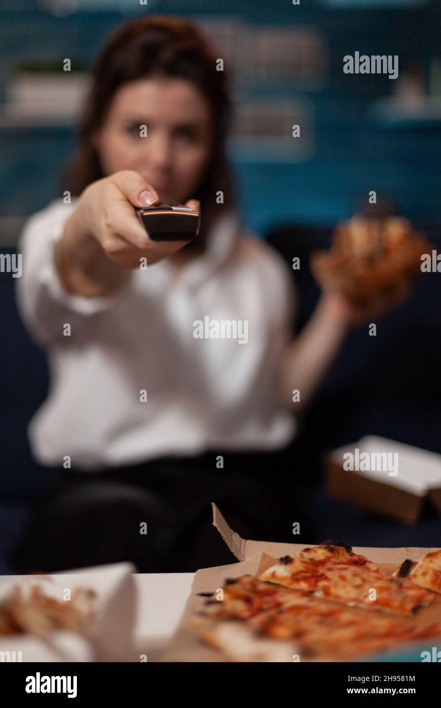 Closeup view of woman hand holding television remote control to change ...