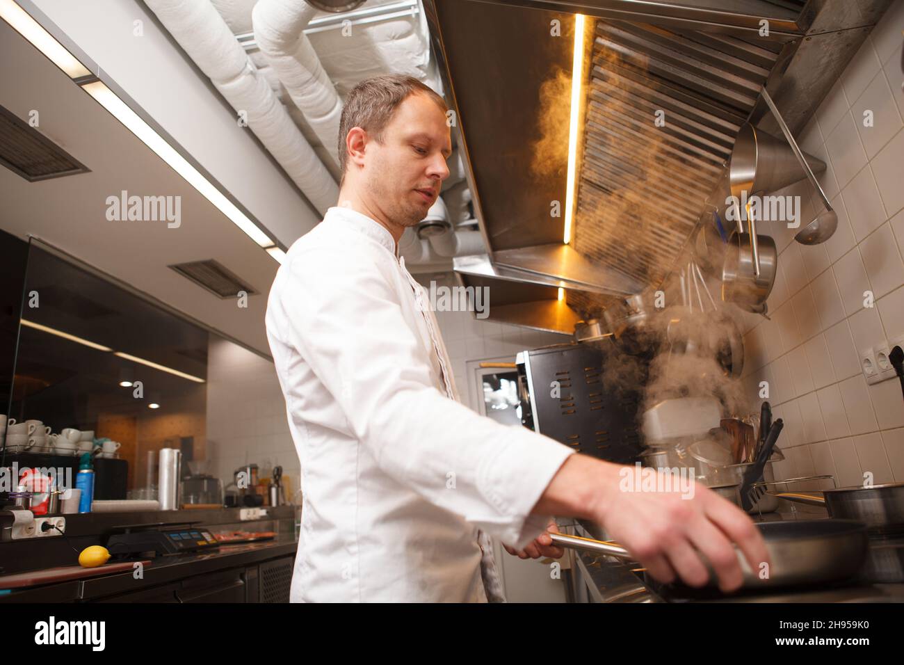 Low angle shot of a male chef using stove, cooking at restaurant ...