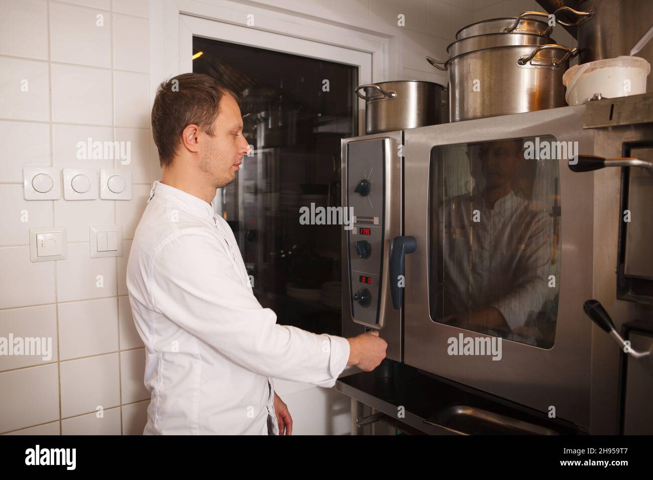 Professional chef using baking oven at his restaurant kitchen Stock ...