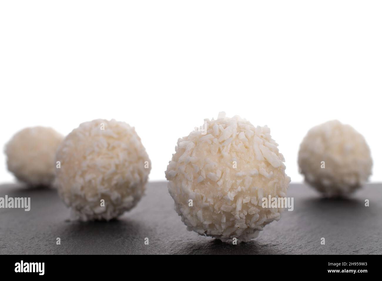 Several sweet sweets with coconut flakes on a slate board, close-up ...