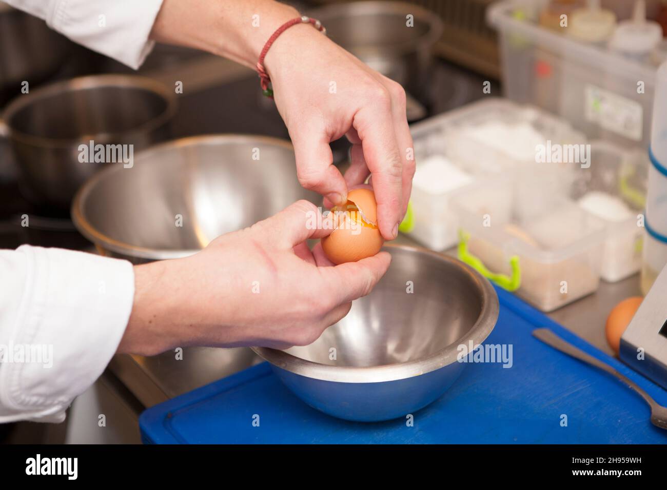 Close up of a chef cracking an egg open into metal bowl Stock Photo - Alamy