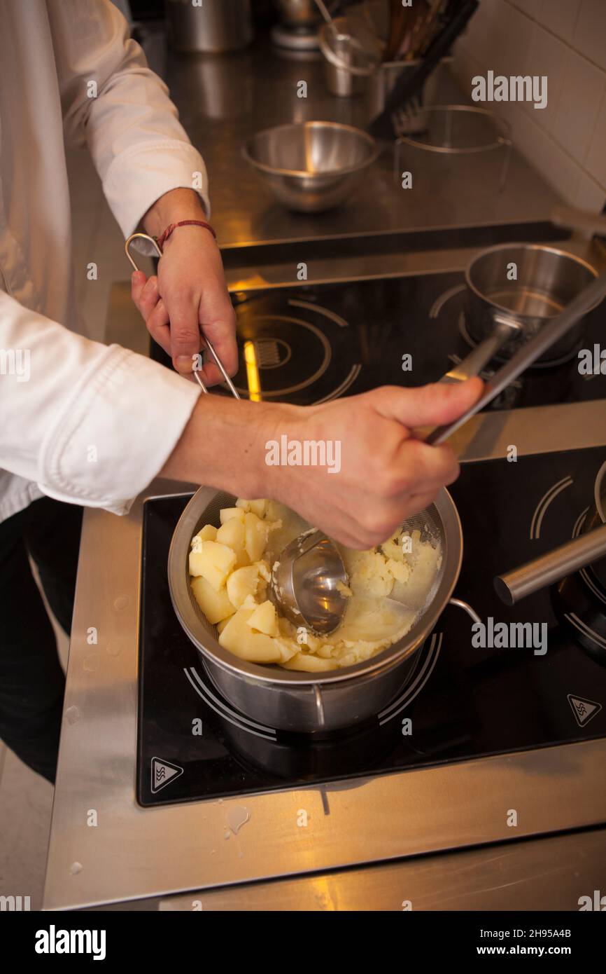Vertical top view shot of unrecognizable chef mashing boiled potatoes ...