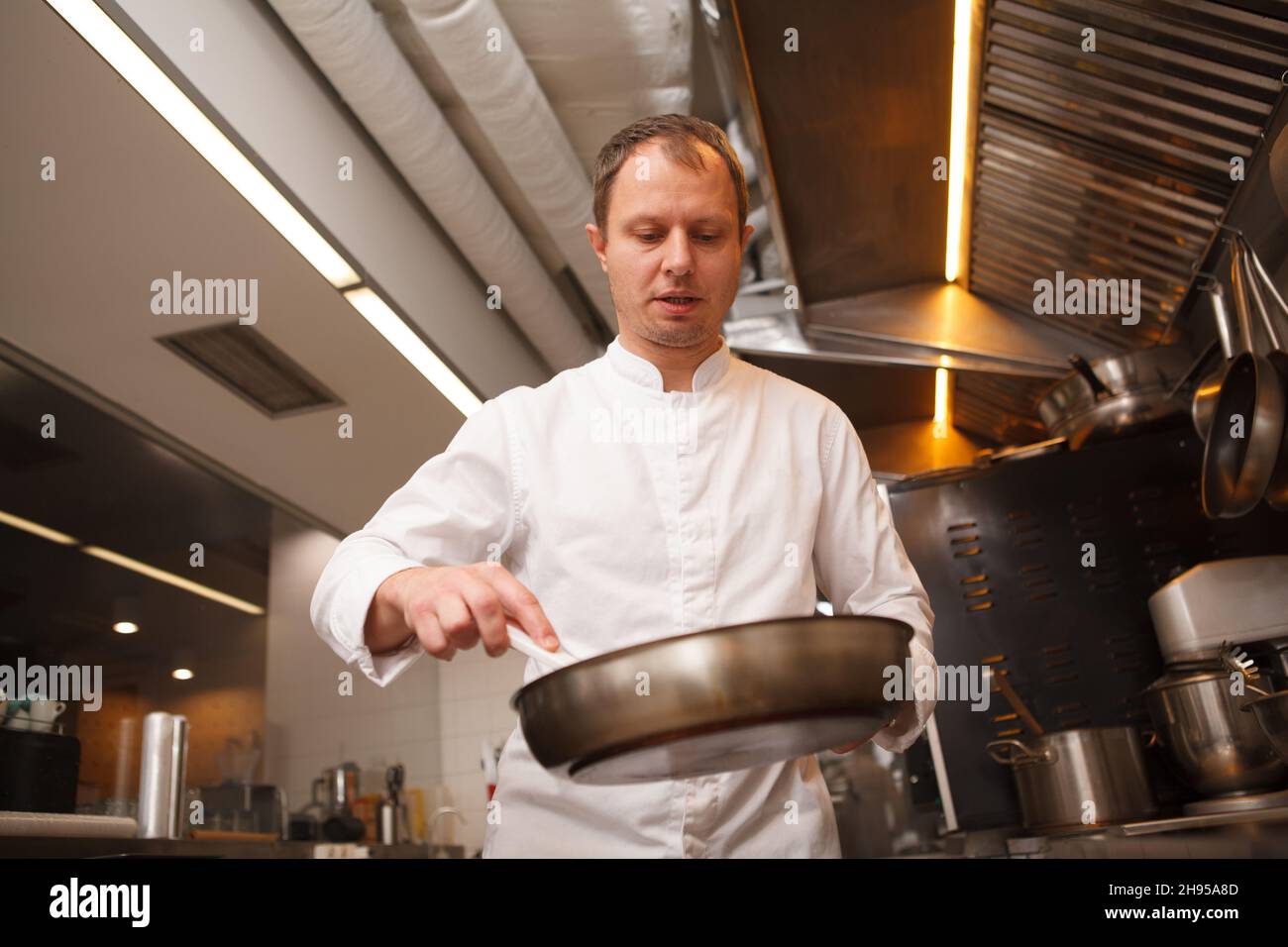 Low angle shot of a restaurant chef cooking at the kitchen, using ...