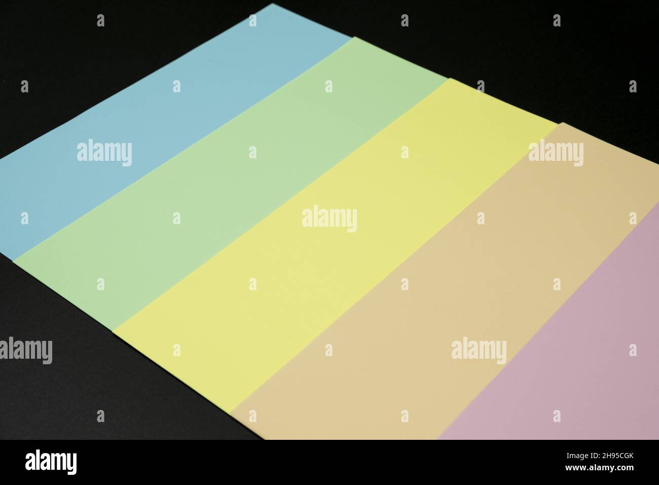 Pastel-colored paper background on black surface with space for text ...