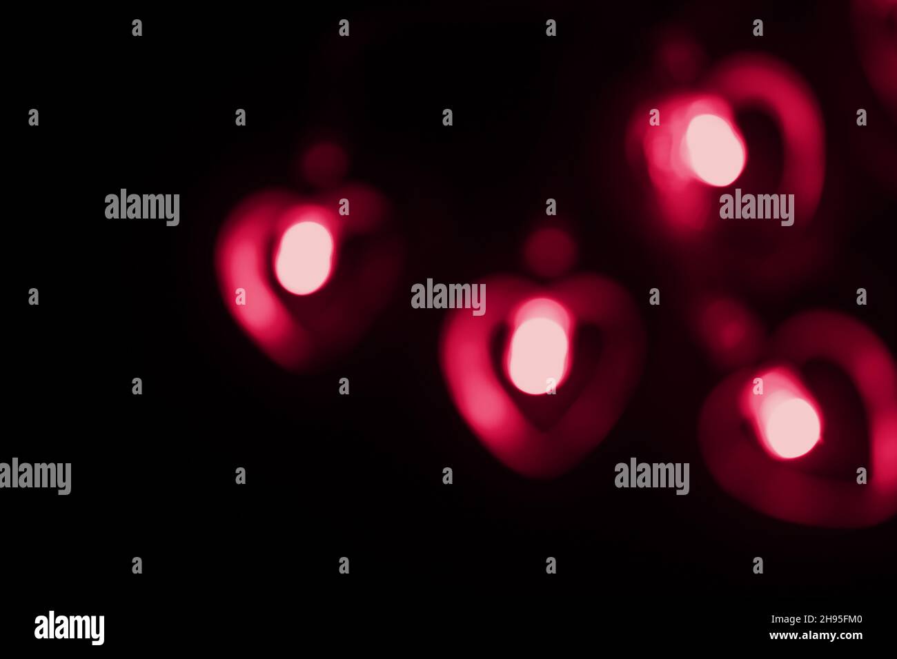 Four large red blurry red lights in the shape of a heart on a black ...