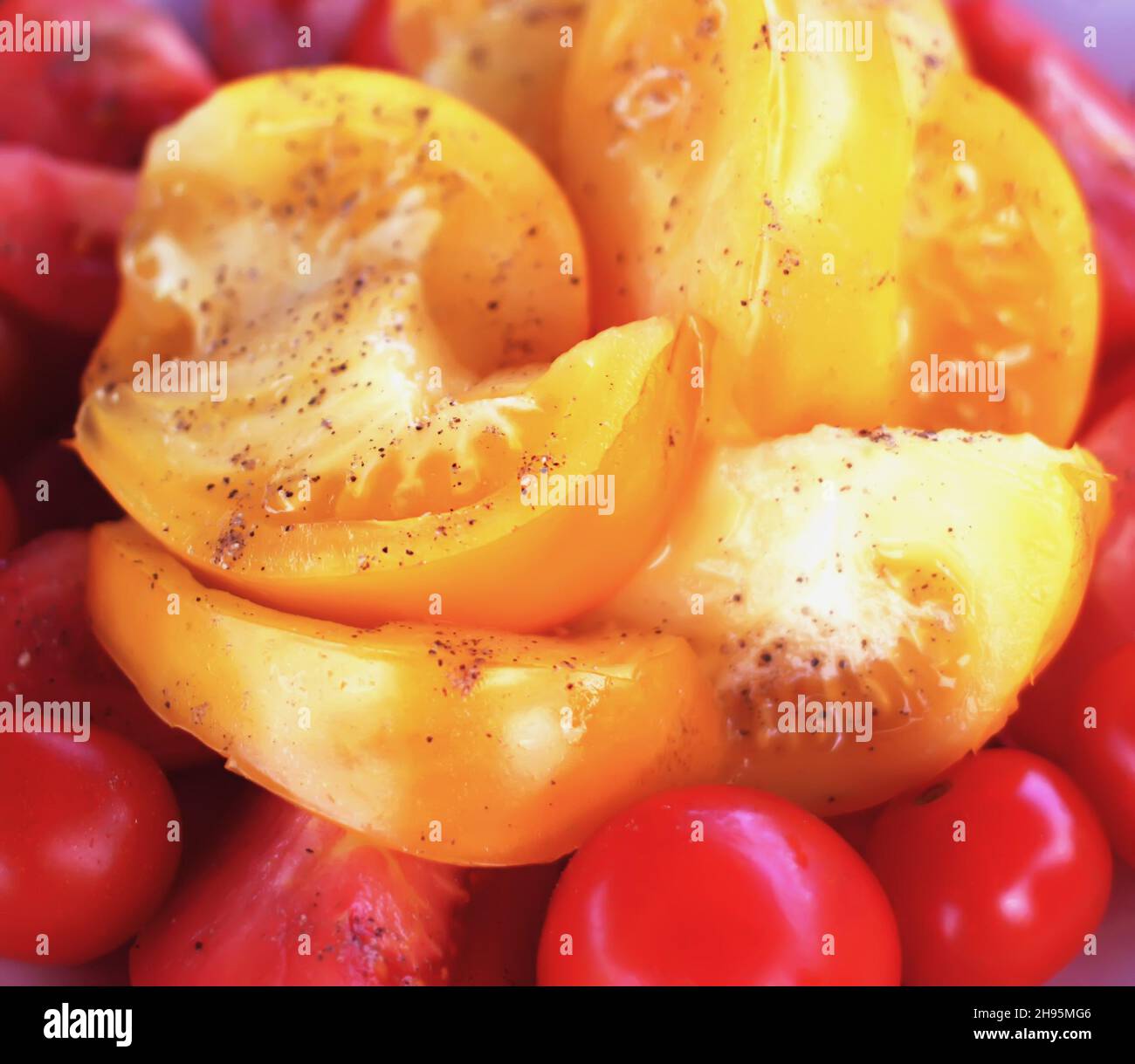 Sliced red and yellow tomatoes with pepper close up Stock Photo - Alamy