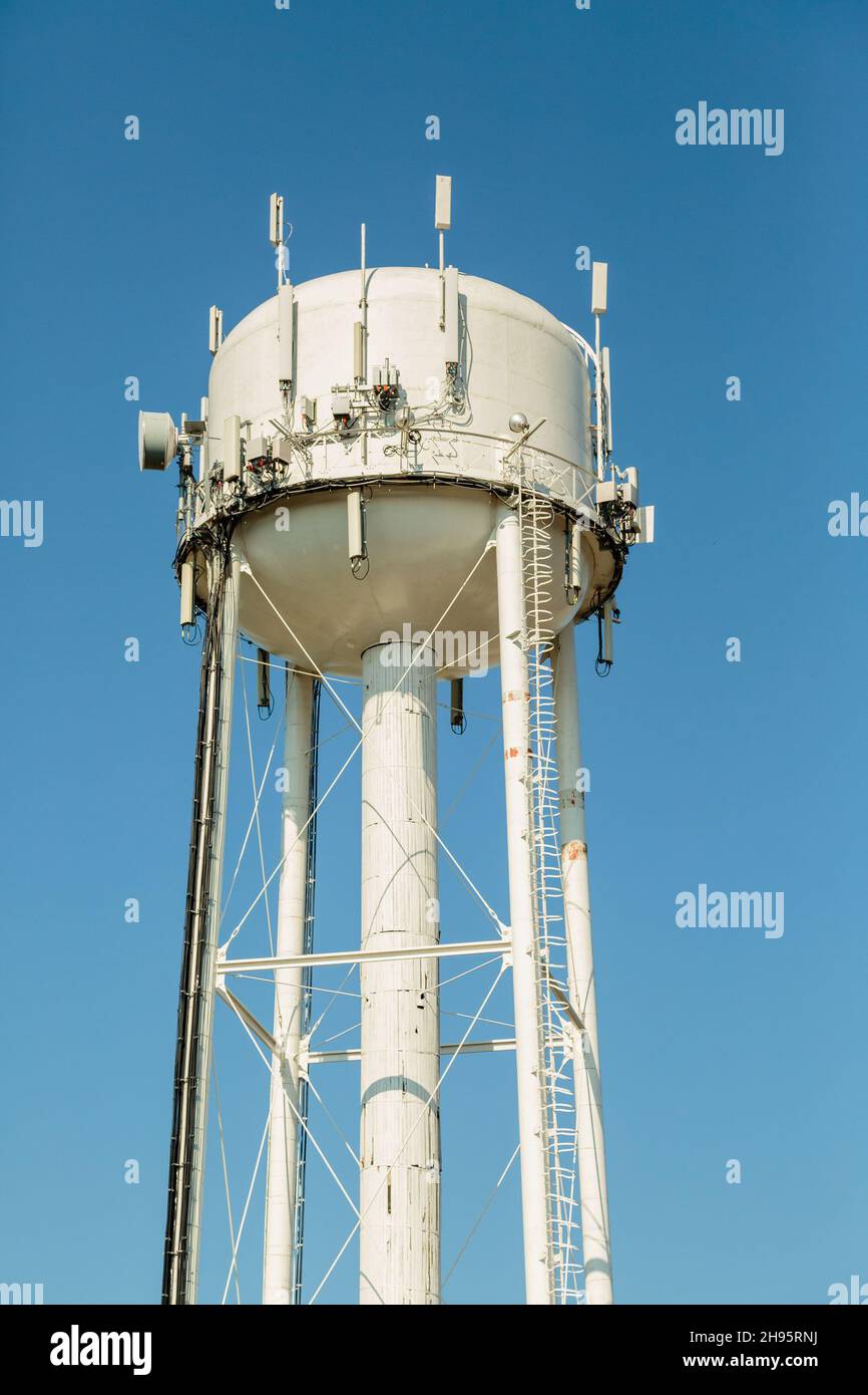 Water tower with dish and antennas for telecommunication on a blue sky ...