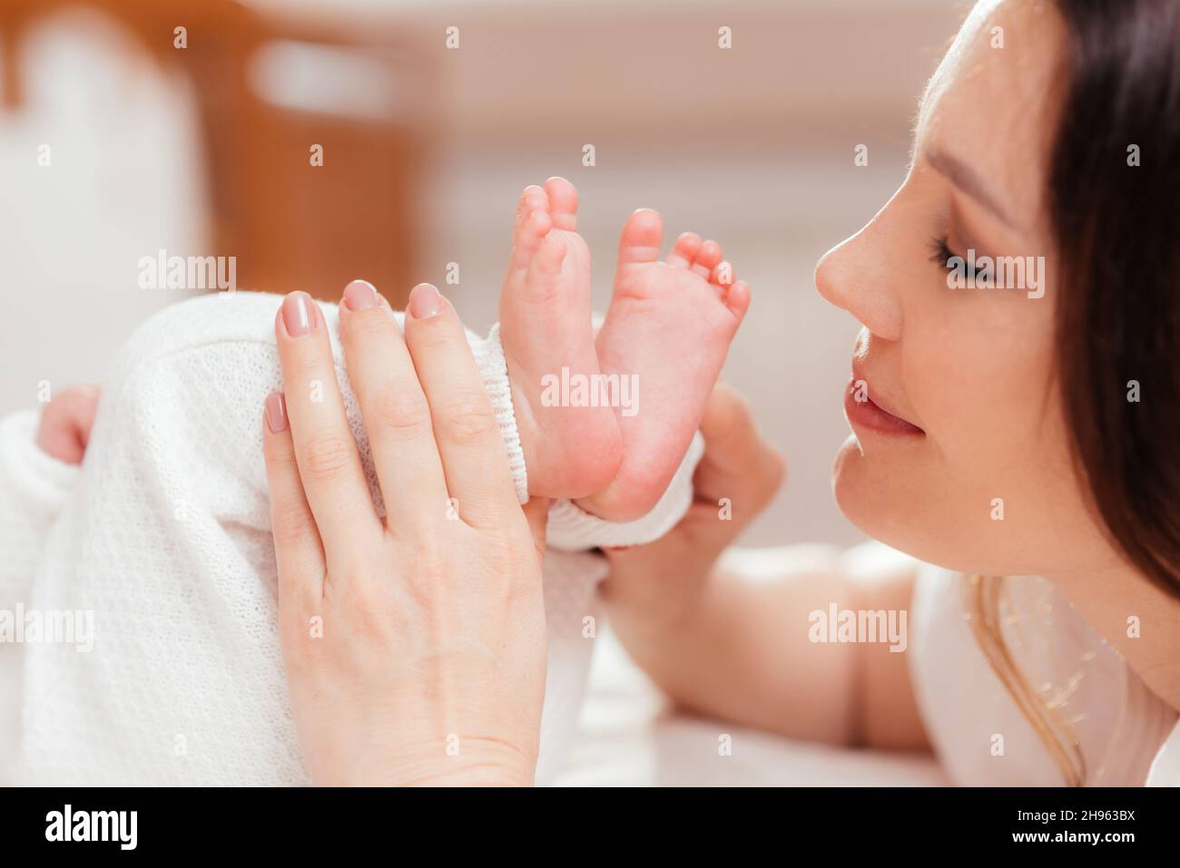 Woman touching feet of newborn baby with hands Stock Photo - Alamy