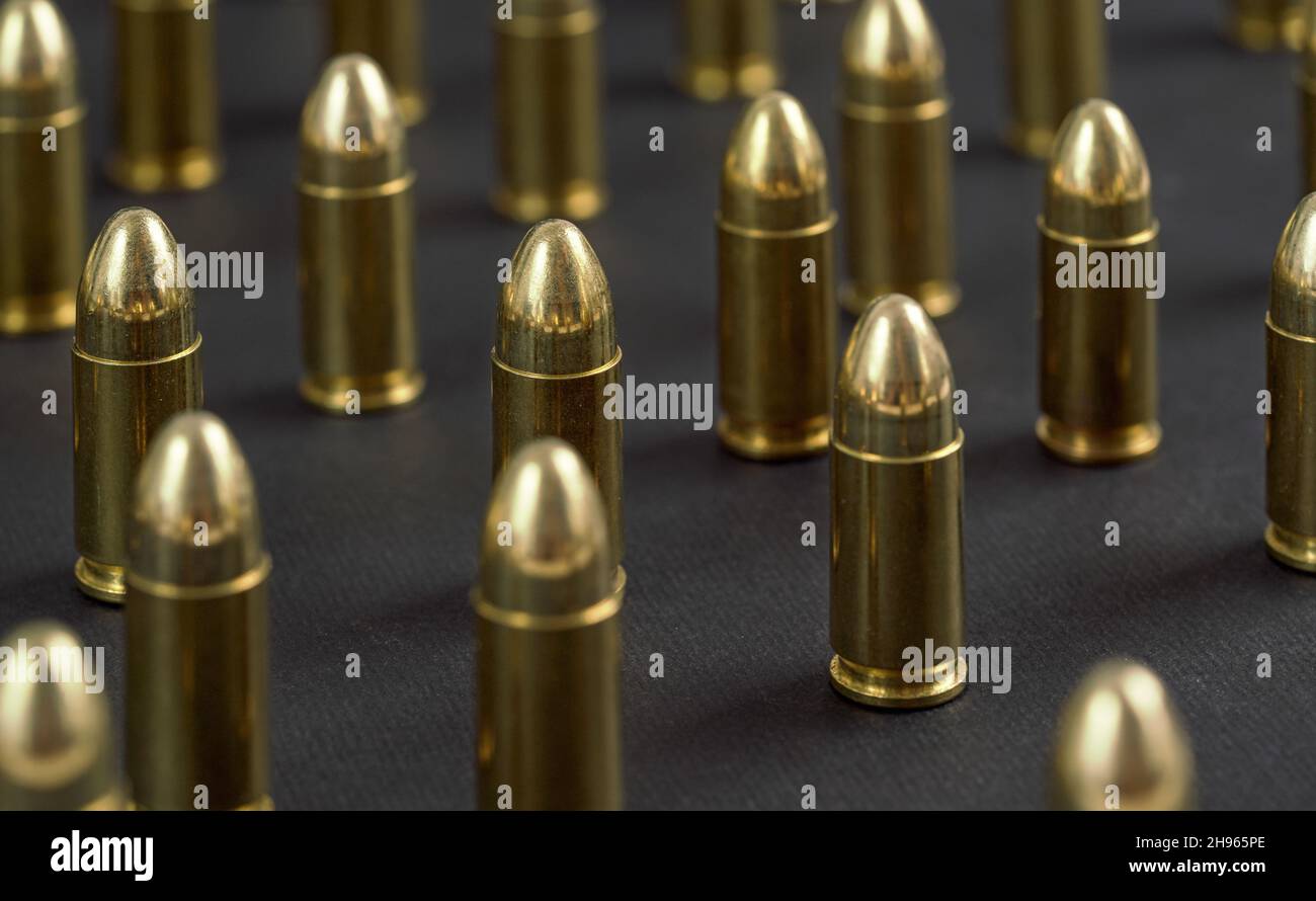 Yellow brass ammo bullets on black desk, arranged standing next to each ...