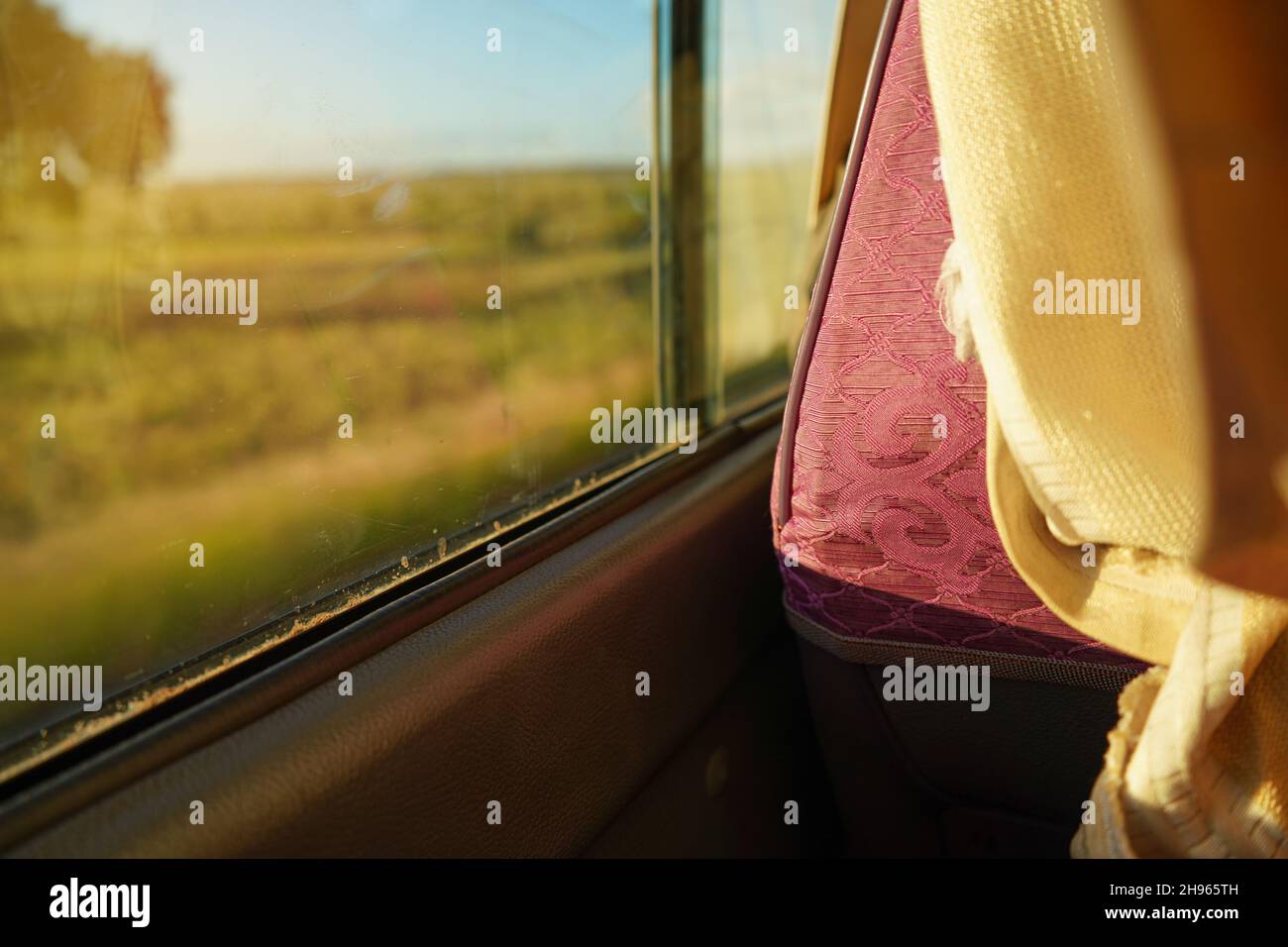 Seat in minibus near window, lit by sun, closeup detail from behind ...