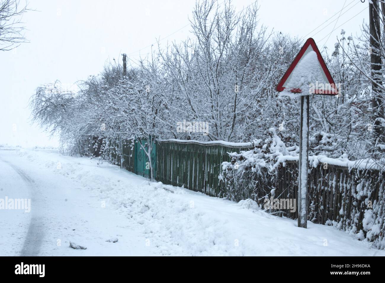 Snow covered road and trees. Road sign covered with snow Stock Photo ...