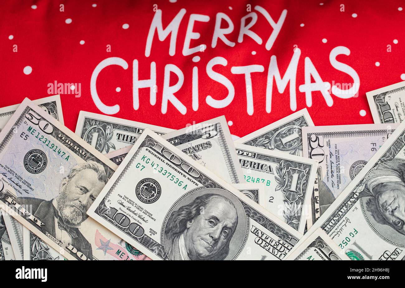 US dollar banknotes and Merry Christmas text on red background for ...
