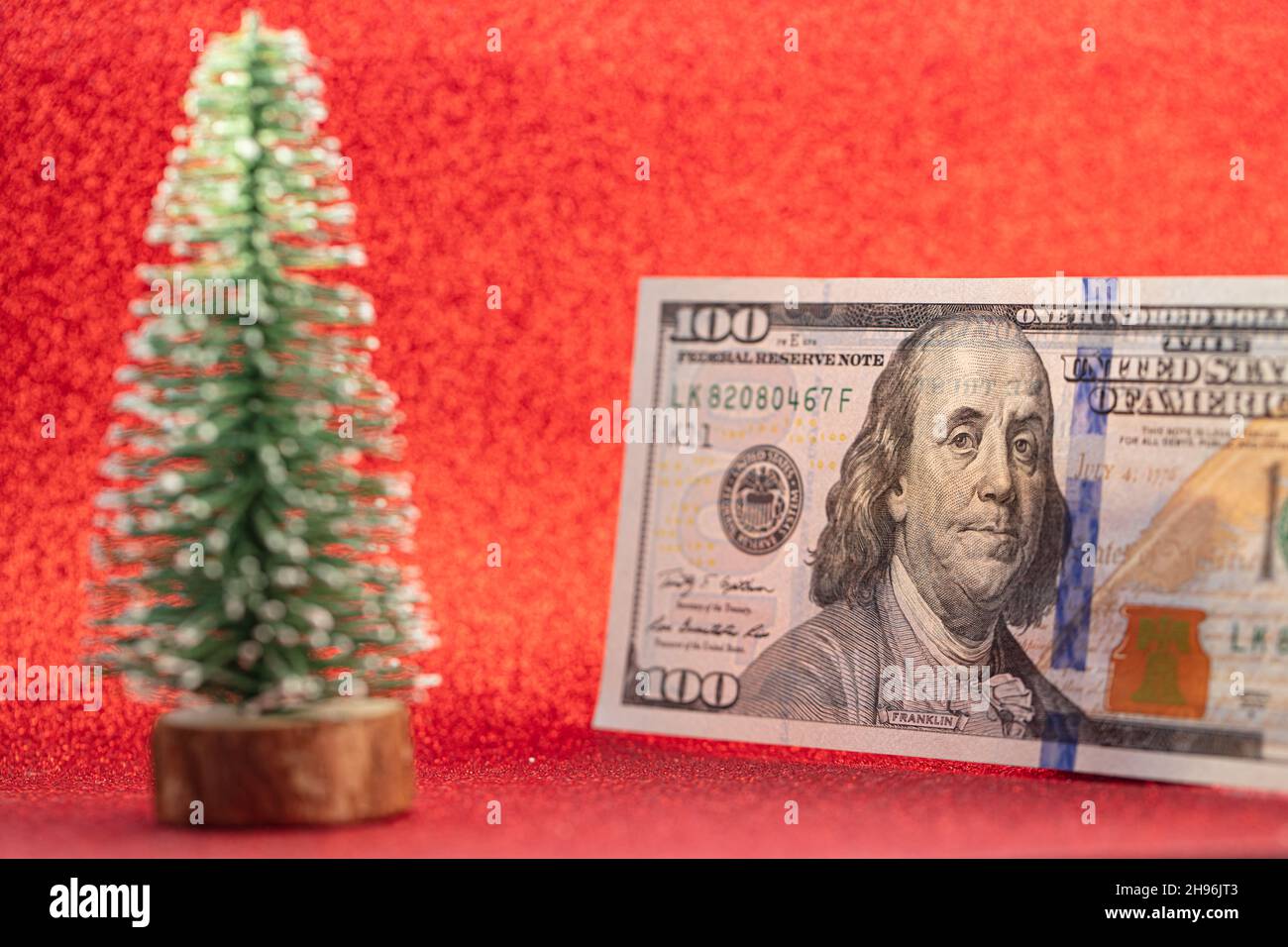 100 dollar bill and toy fir tree on red background for design purpose ...