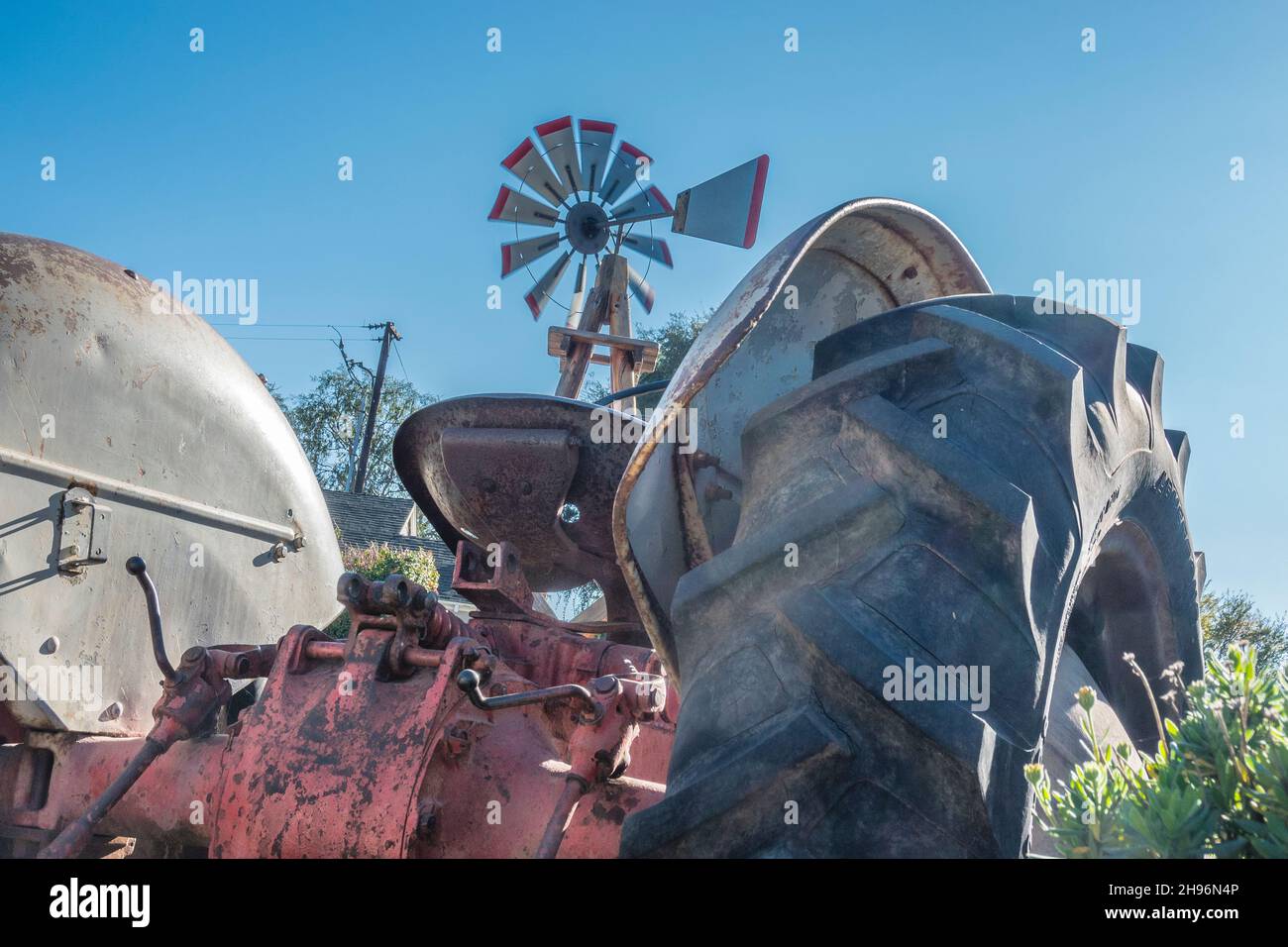 A detail of antique tractor with an old windmill in the background in ...
