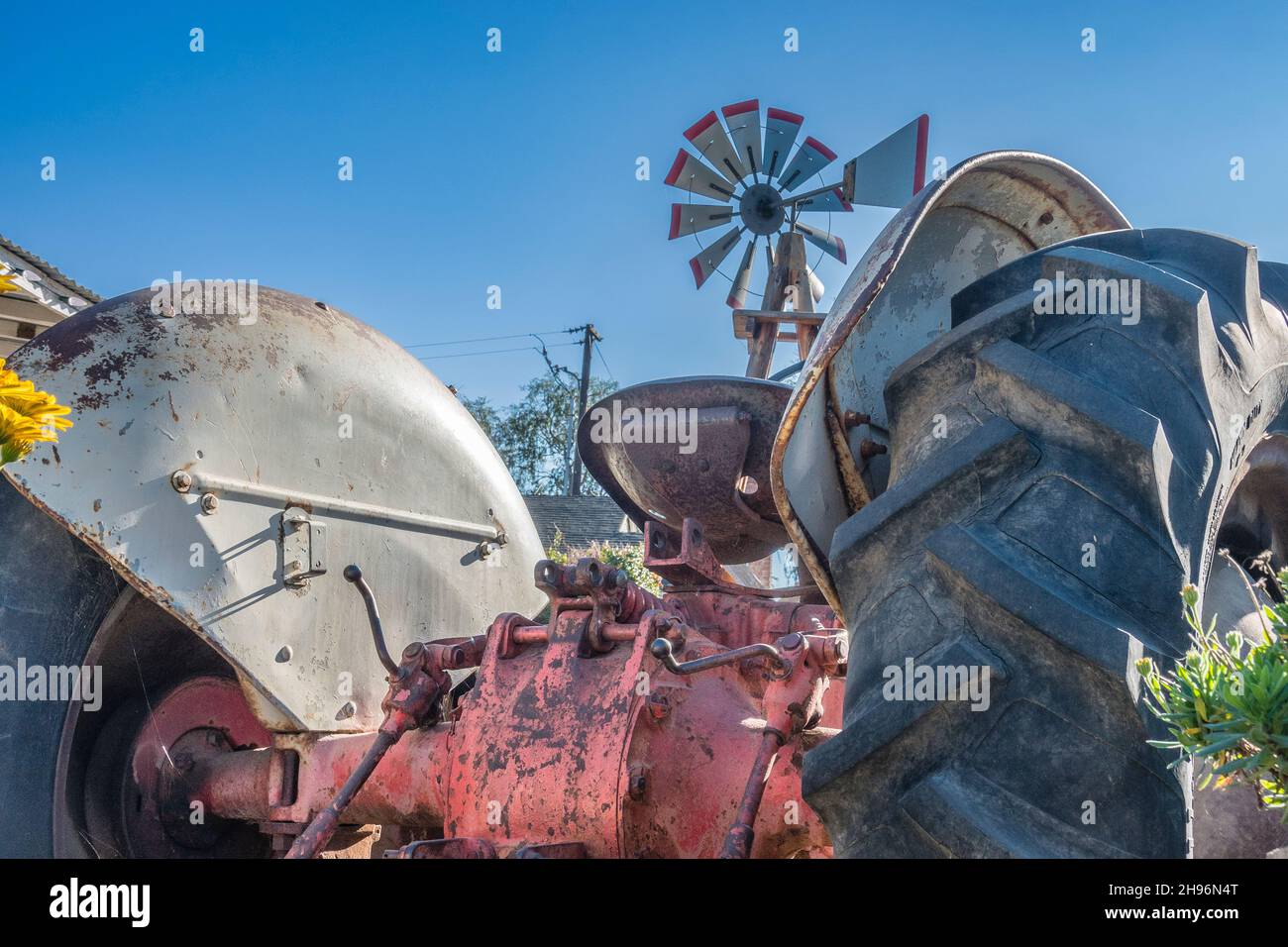 A detail of antique tractor with an old windmill in the background in ...