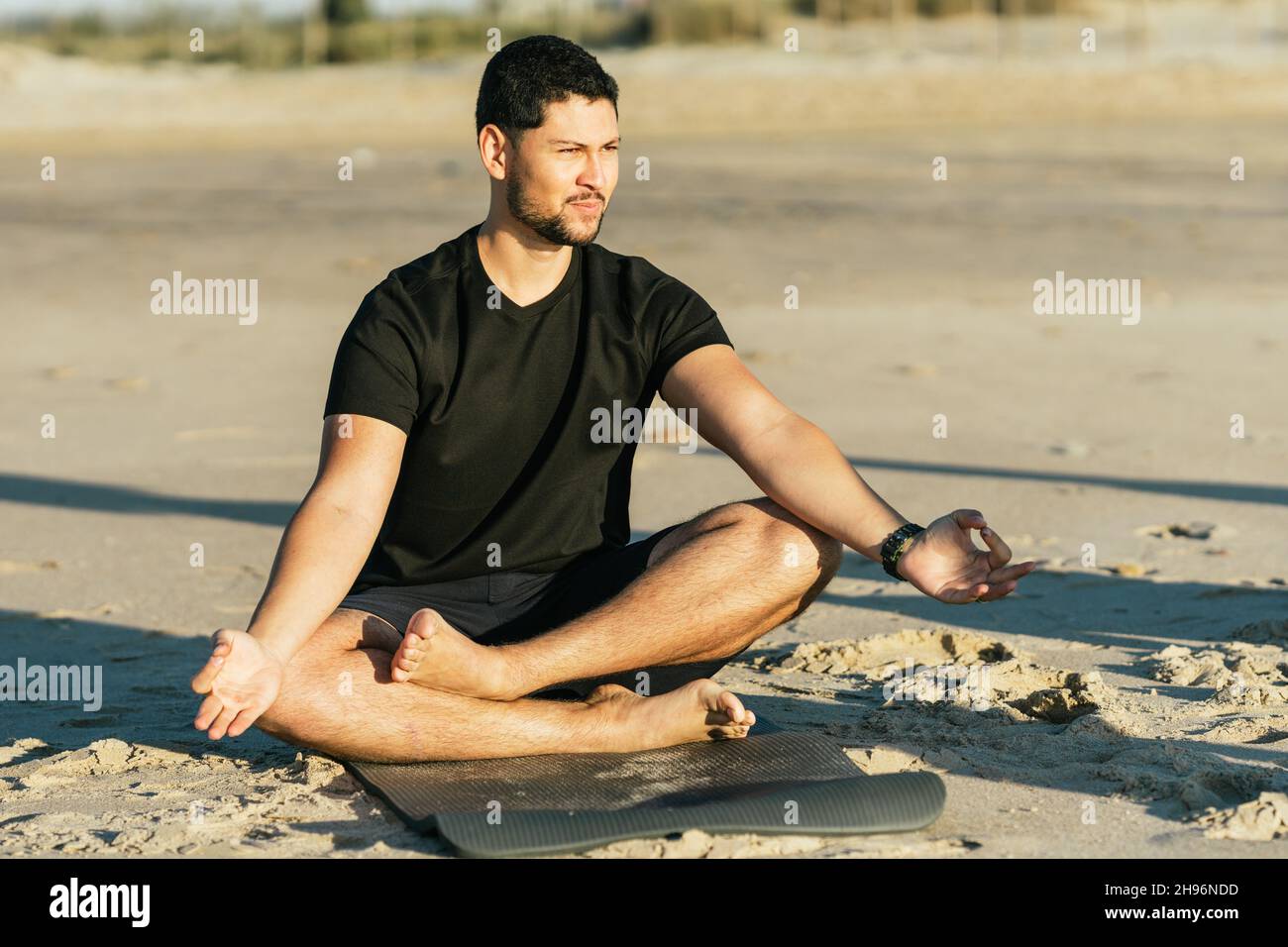 Man doing the lotus position of yoga facing the sun on the beach Stock ...