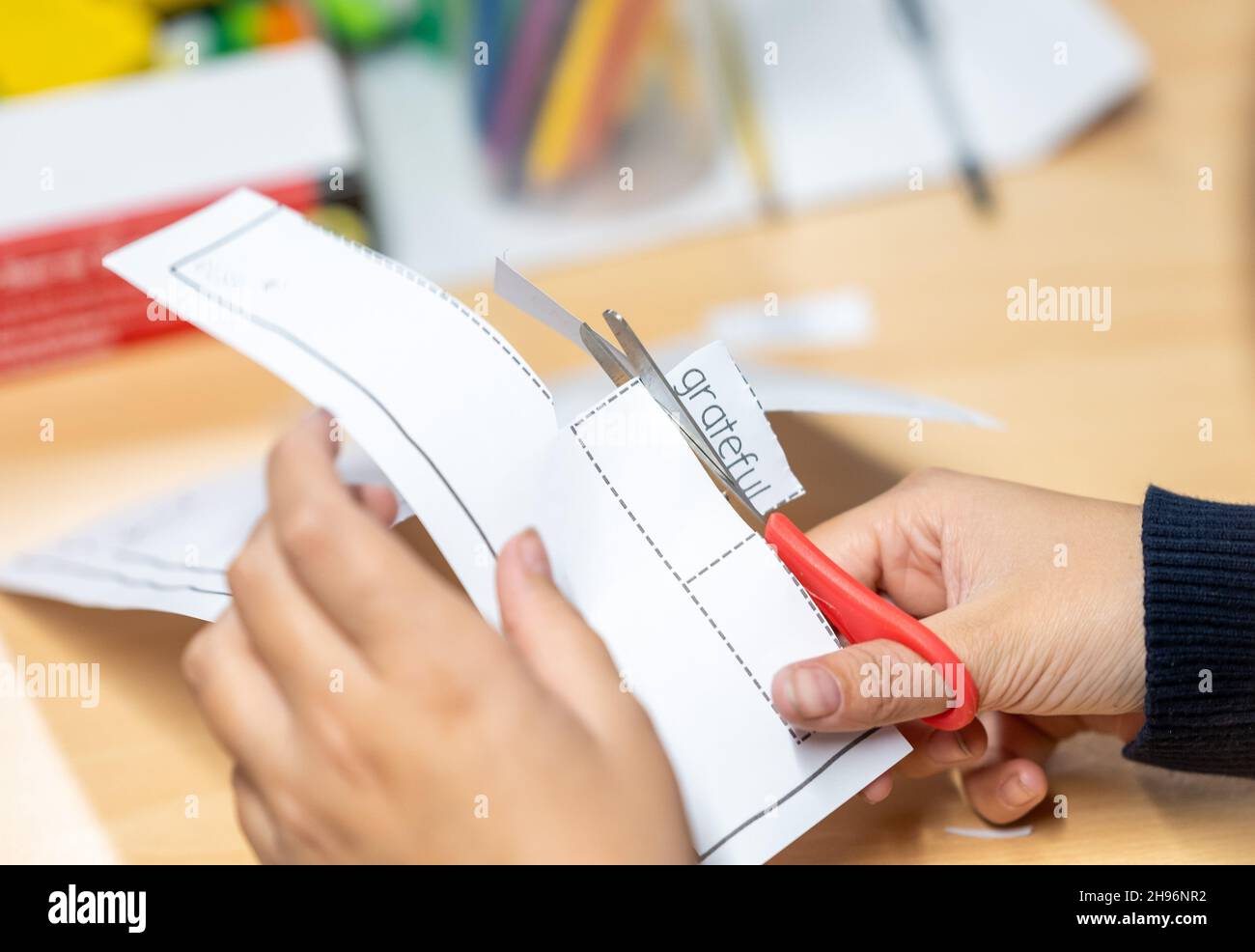 A child cuts up a piece of paper in a school classroom in the UK Stock ...