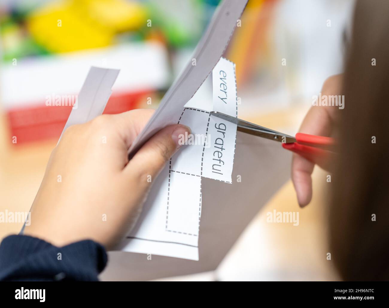 A child cuts up a piece of paper in a school classroom in the UK Stock ...