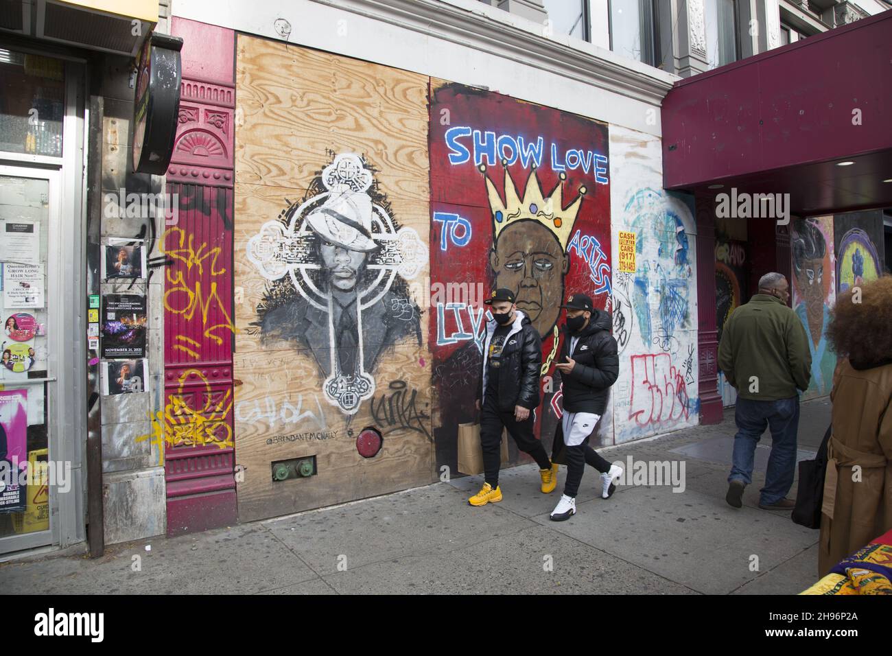 People walk along 125th Street in Harlem by a portrait of a crowned ...