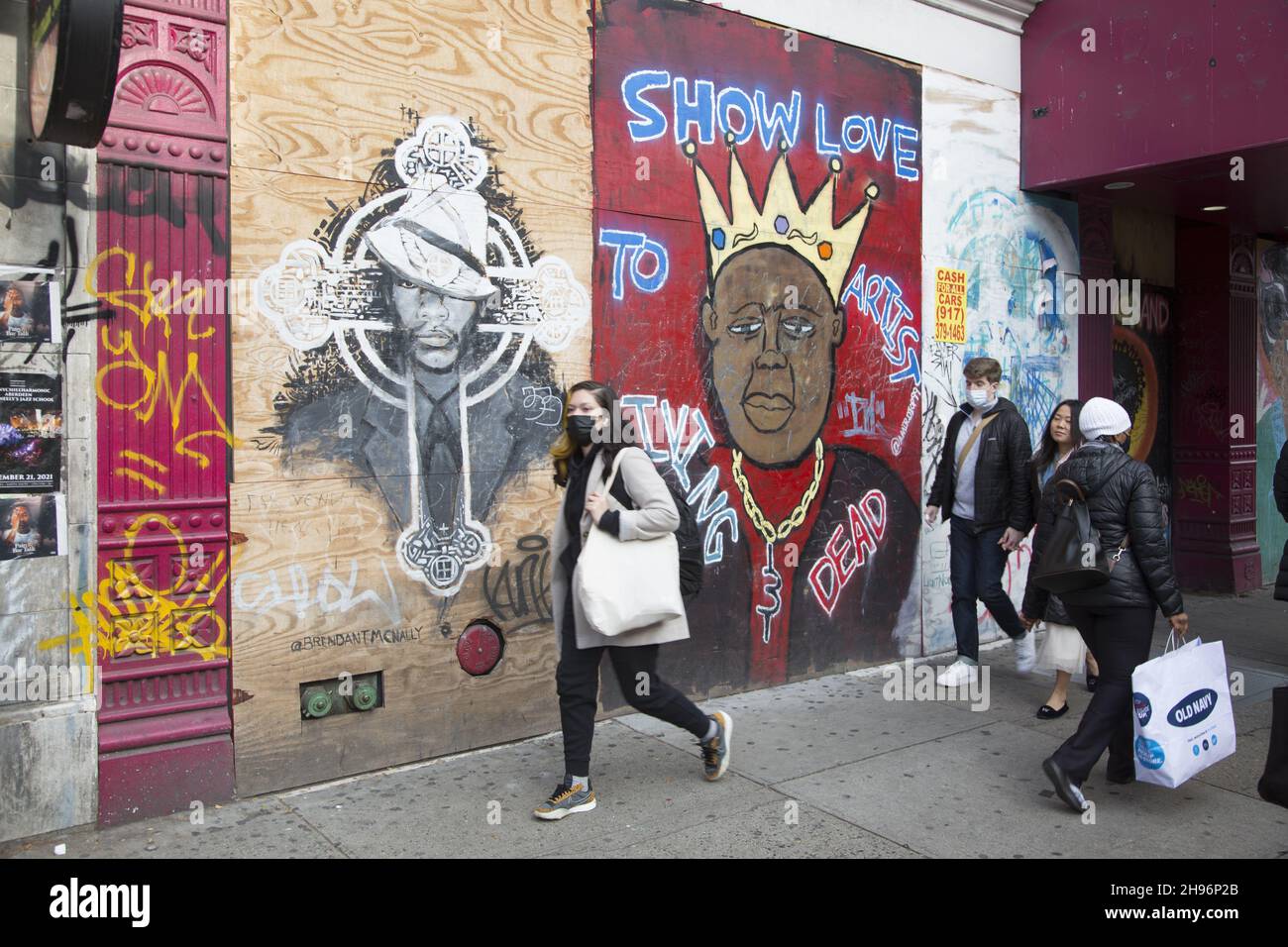 People walk along 125th Street in Harlem by a portrait of a crowned ...