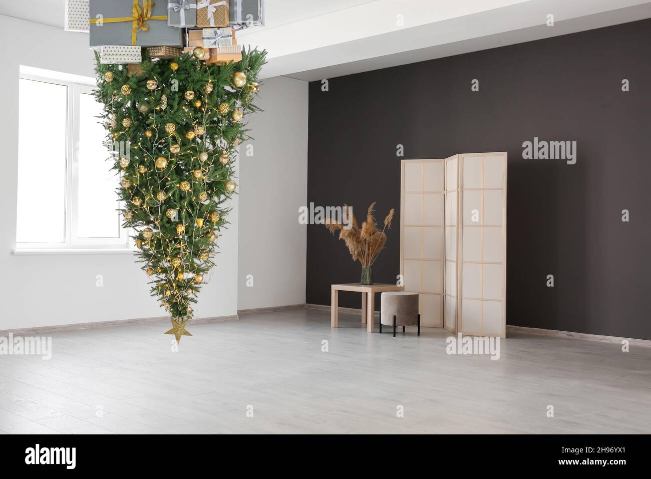 Beautiful Christmas tree with gift boxes hanging on ceiling in room ...