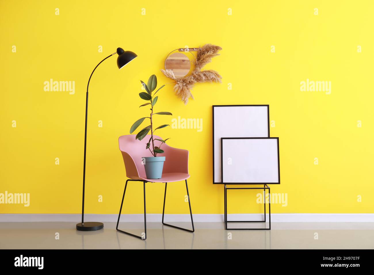 Blank poster with stylish chair near color wall Stock Photo - Alamy