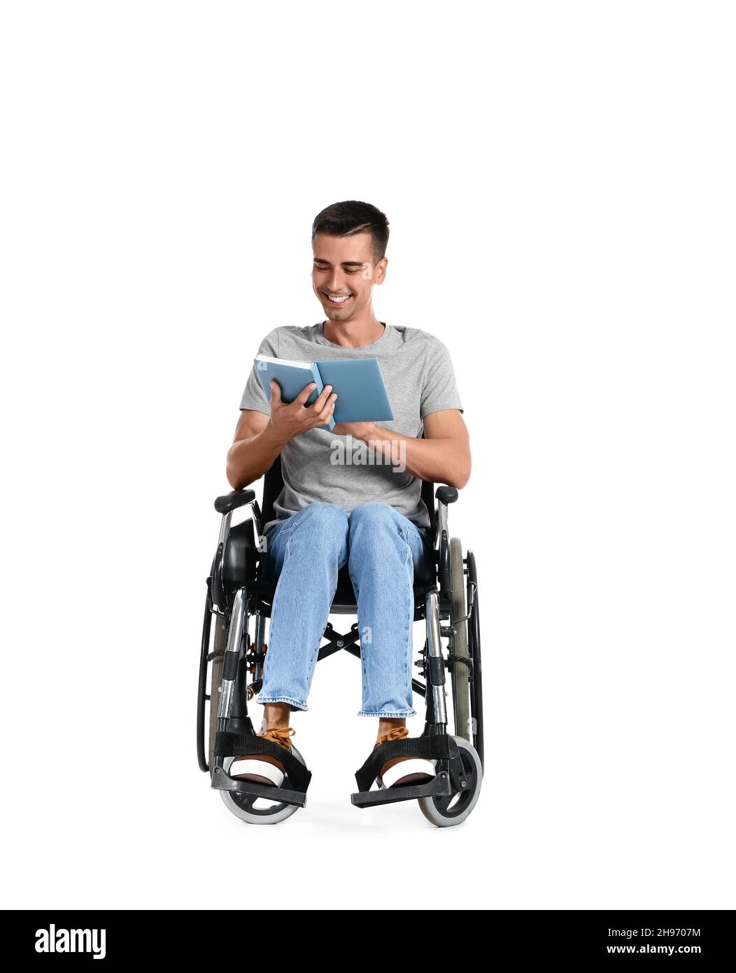 Young man in wheelchair reading book on white background Stock Photo ...