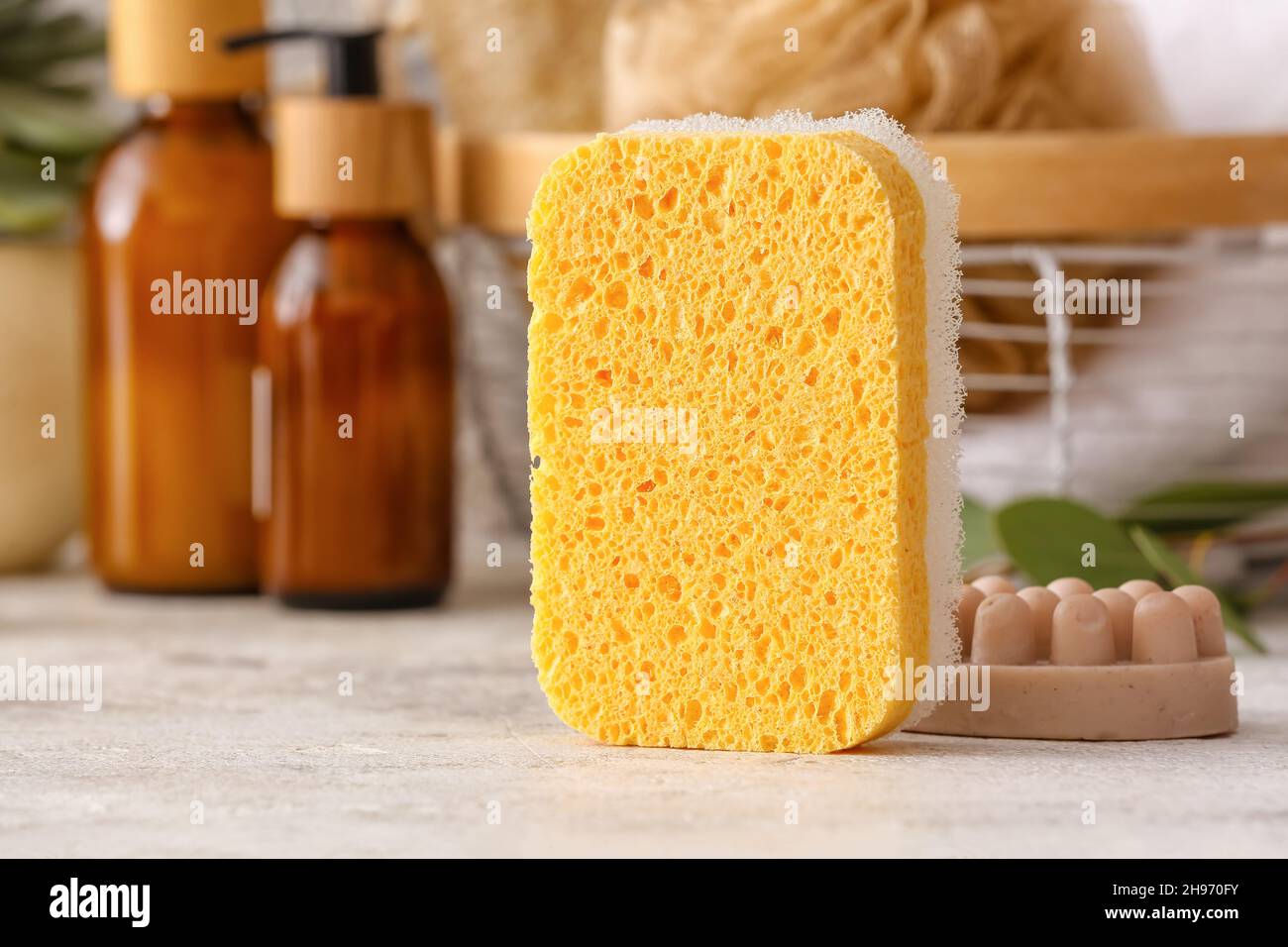 Bath sponge, massage soap bar and bottles of cosmetic products on light ...