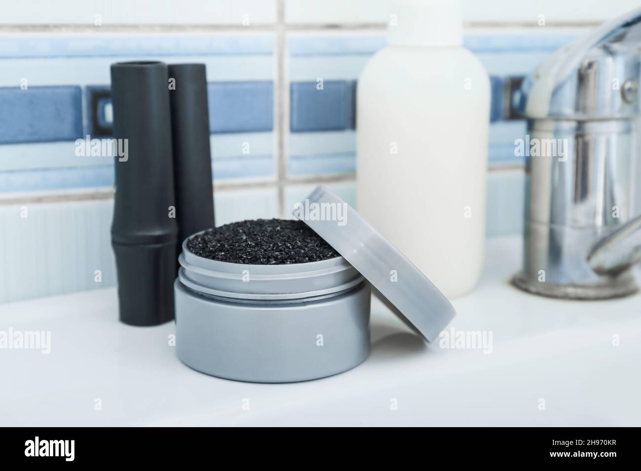 Jar with activated charcoal tooth powder on sink in bathroom Stock ...