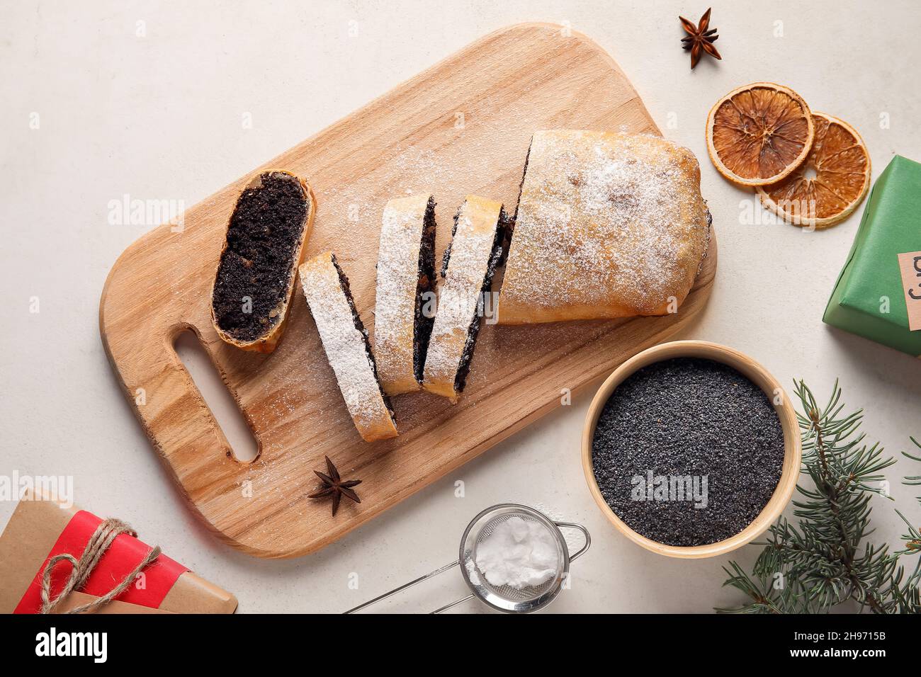 Wooden board with cut poppy seed strudel on light background Stock ...