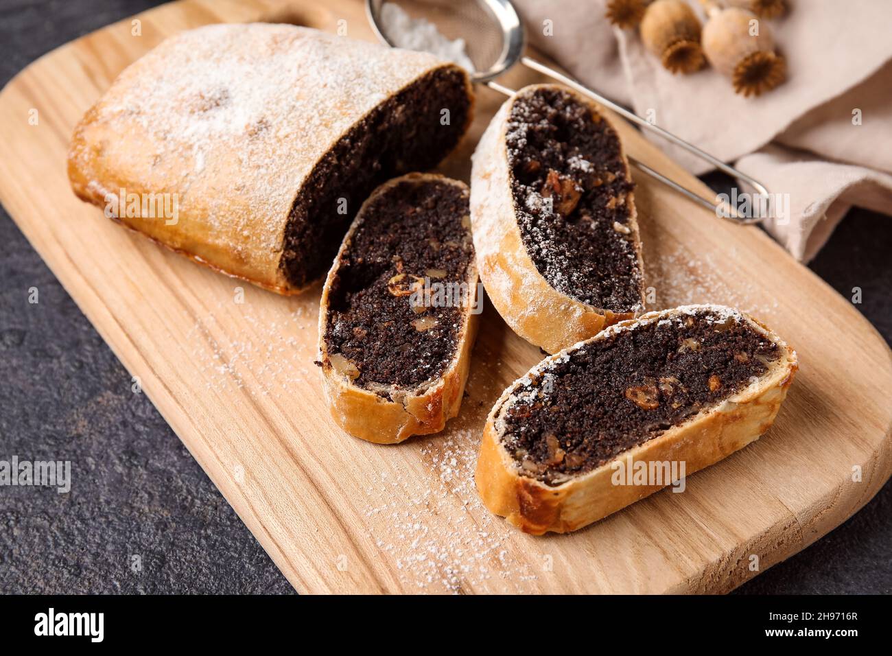 Wooden board with cut poppy seed strudel on black background Stock ...
