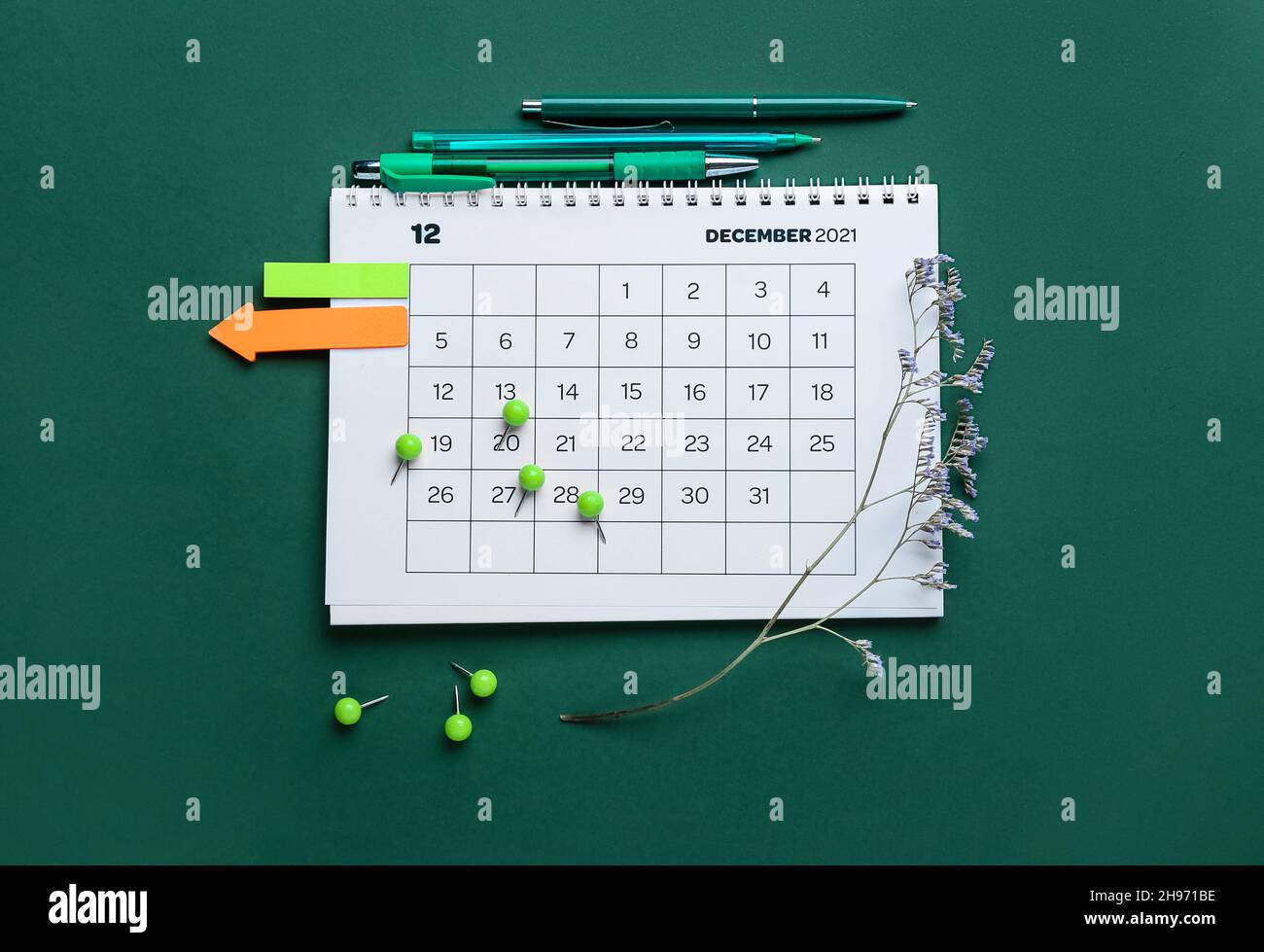 Flip paper calendar for December 2021, sticky notes, pens, pins and ...