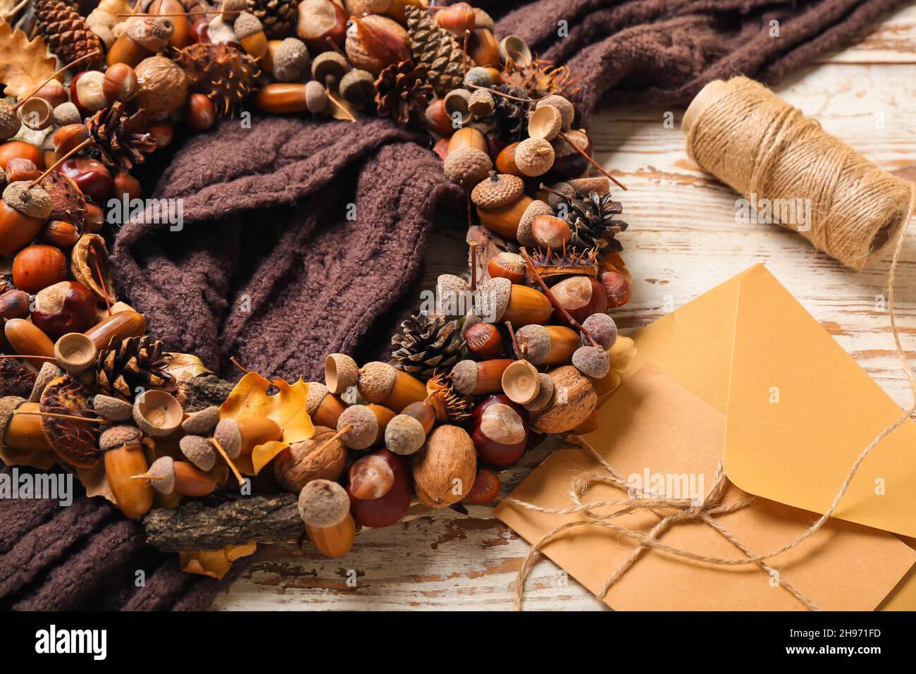 Beautiful acorn wreath with envelope and scarf on white wooden ...