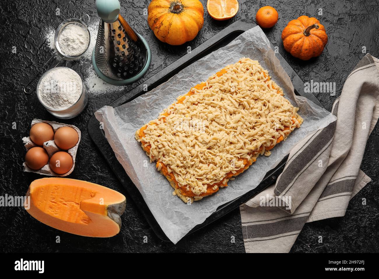 Baking dish with uncooked pumpkin pie and ingredients on black ...