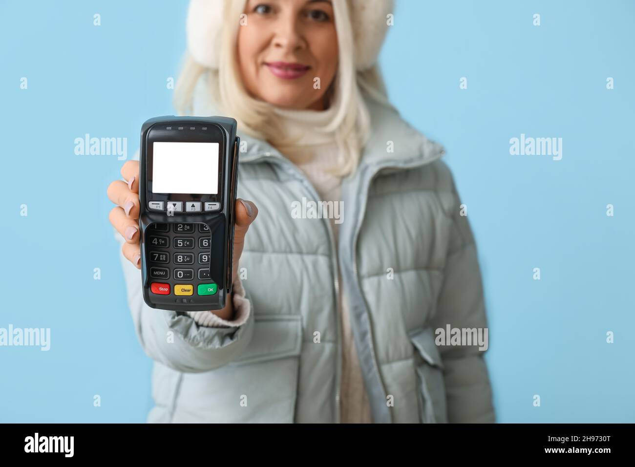 Mature woman with banking terminal on color background Stock Photo - Alamy