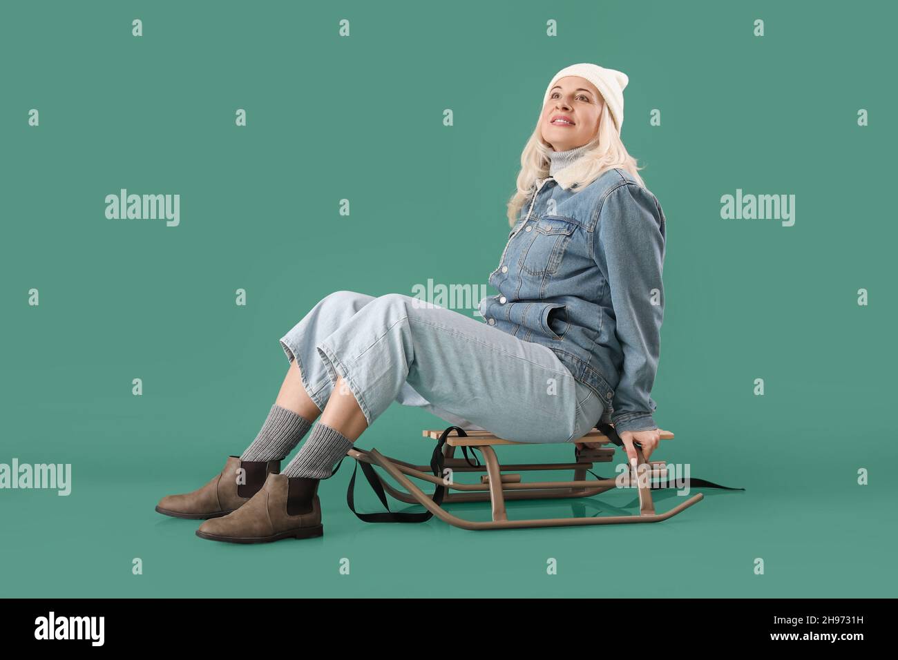 Beautiful mature woman with sled on color background Stock Photo - Alamy