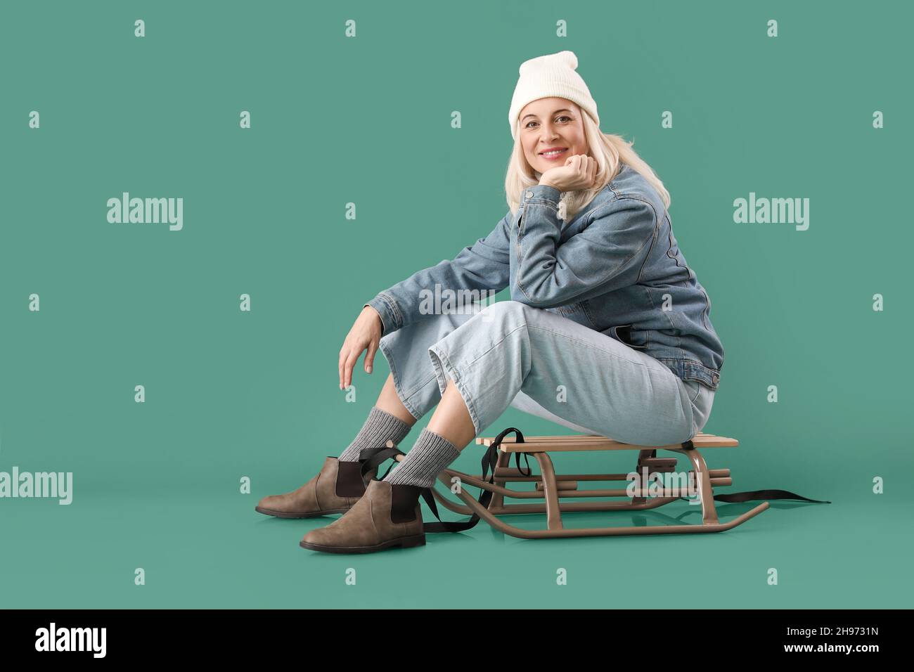 Beautiful mature woman with sled on color background Stock Photo - Alamy