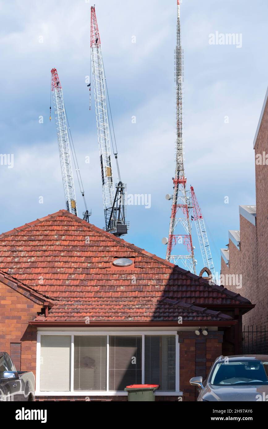 A small brick and terracotta tile roof house with large cranes and a ...