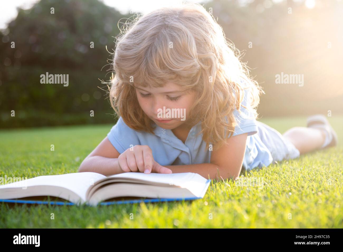 Smart clever Kids. Kid boy reading interest book in the garden ...