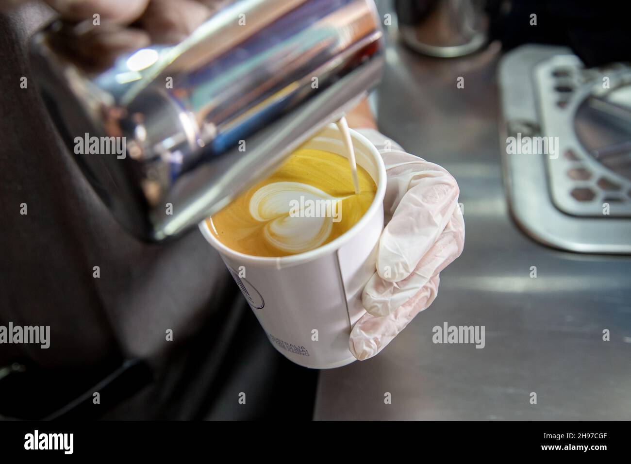 A close-up shot of hands in gloves pouring coffee from a pot into a ...