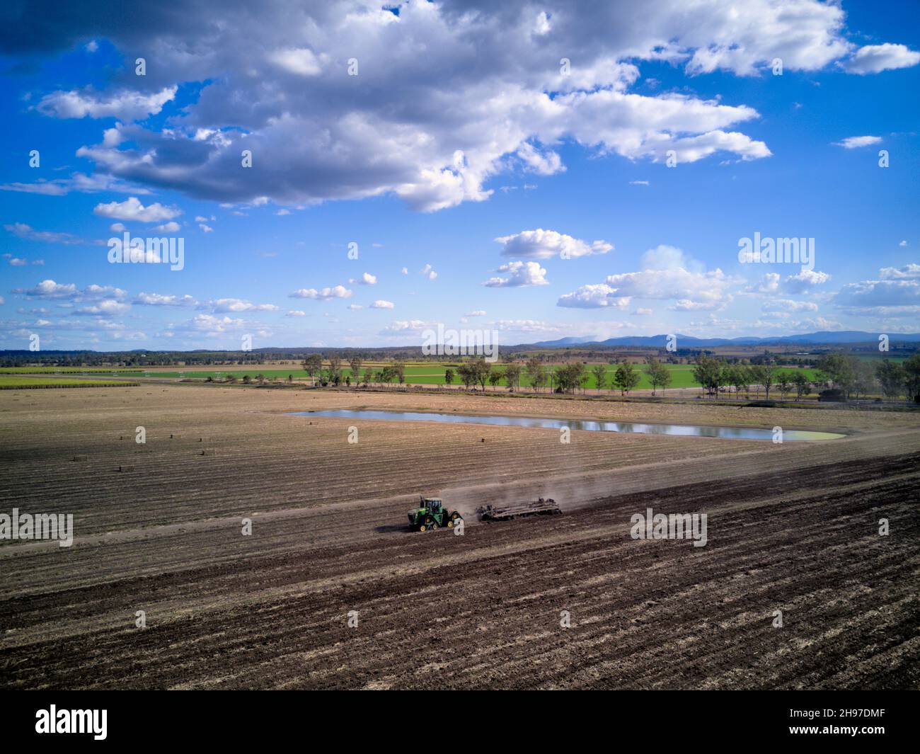 Aerial of broad acre farming tractor preparing ground for planting of ...