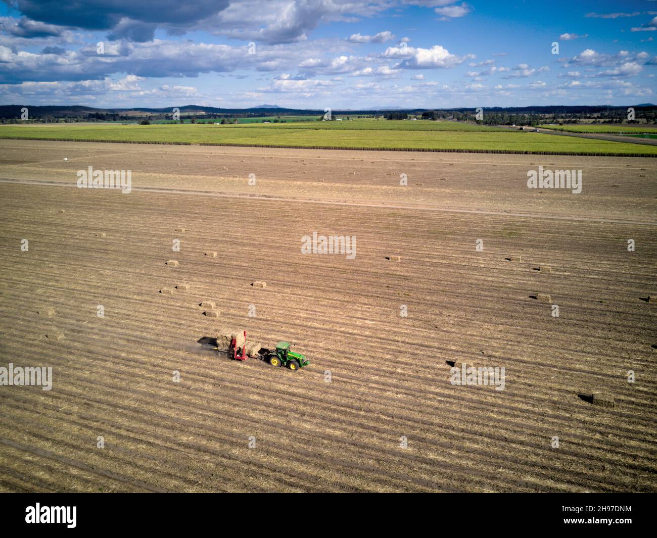 Aerial of broad acre farming tractor collecting baled sugar cane trash ...
