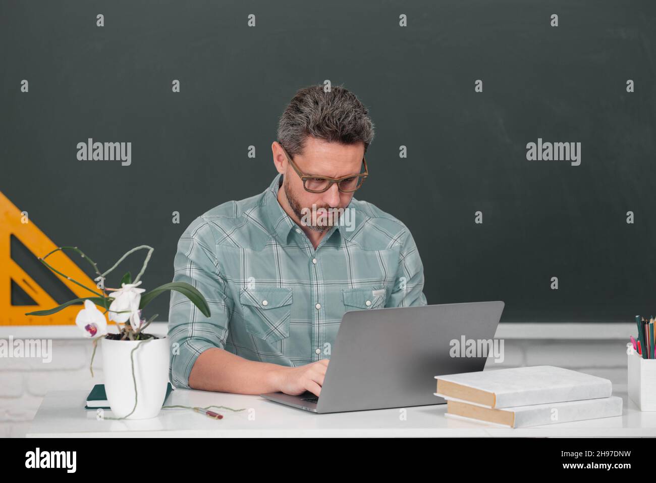 Portrait of confident caucasian male teacher in classroom. Middle aged ...