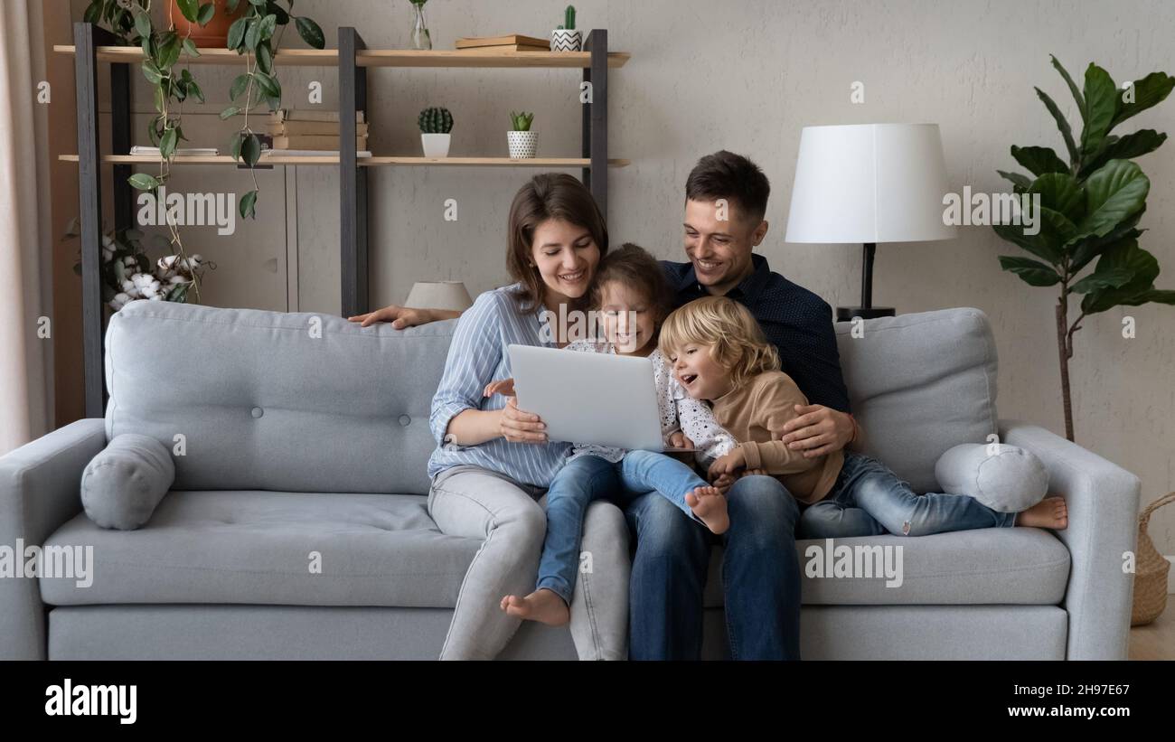 Cheerful millennial parents resting with gen Z kids on couch Stock ...