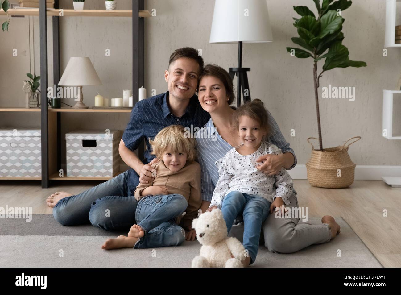Happy parents and two little sibling kids home portrait Stock Photo - Alamy