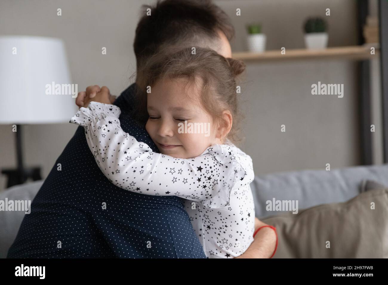Happy peaceful daughter kid embracing beloved dad at home Stock Photo ...