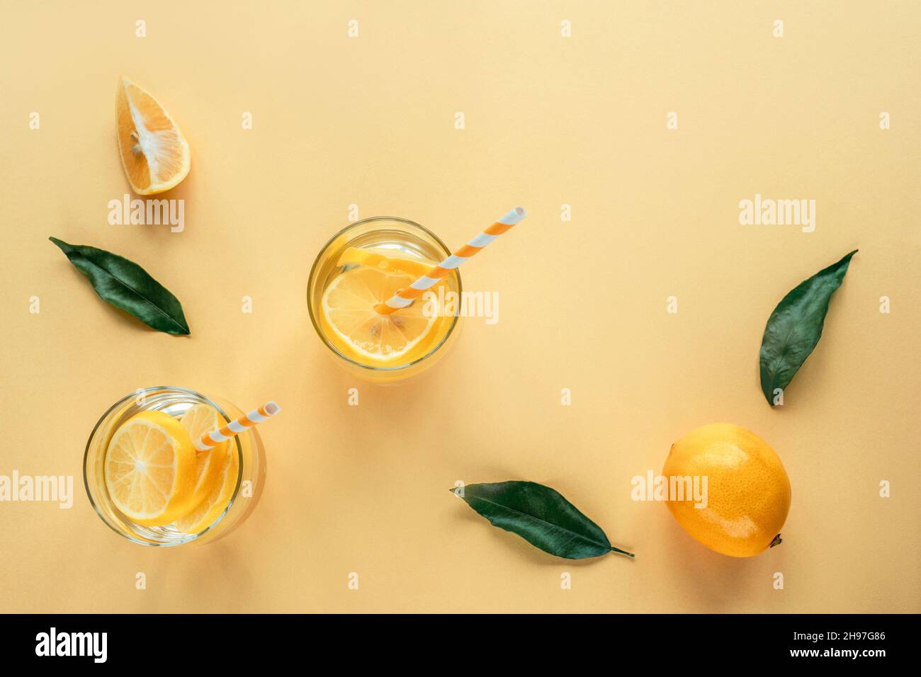 Two glasses of lemonade and pieces of lemon, green leaves on a yellow ...