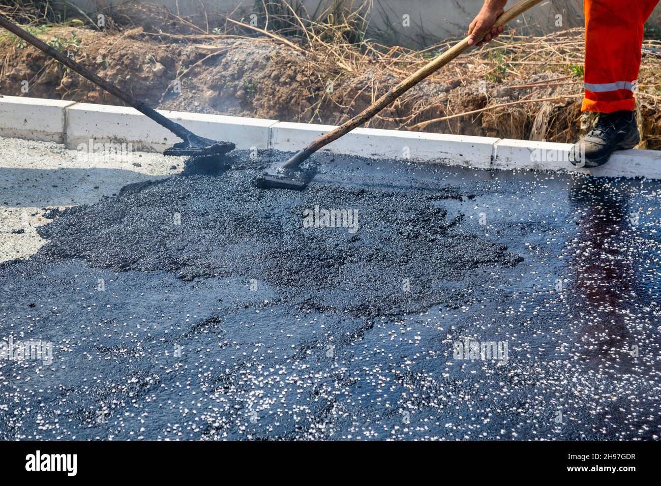 Road construction workers leveling hot asphalt pavement with trowel ...