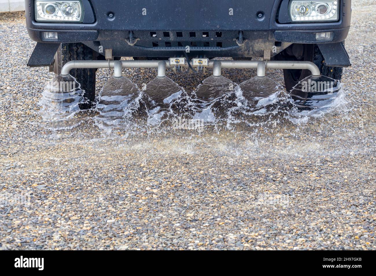 Truck sprays water on new road construction site. Water truck spraying ...